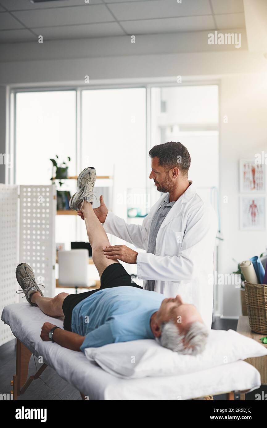 Testing the movement in all his muscles. a young male physiotherapist ...