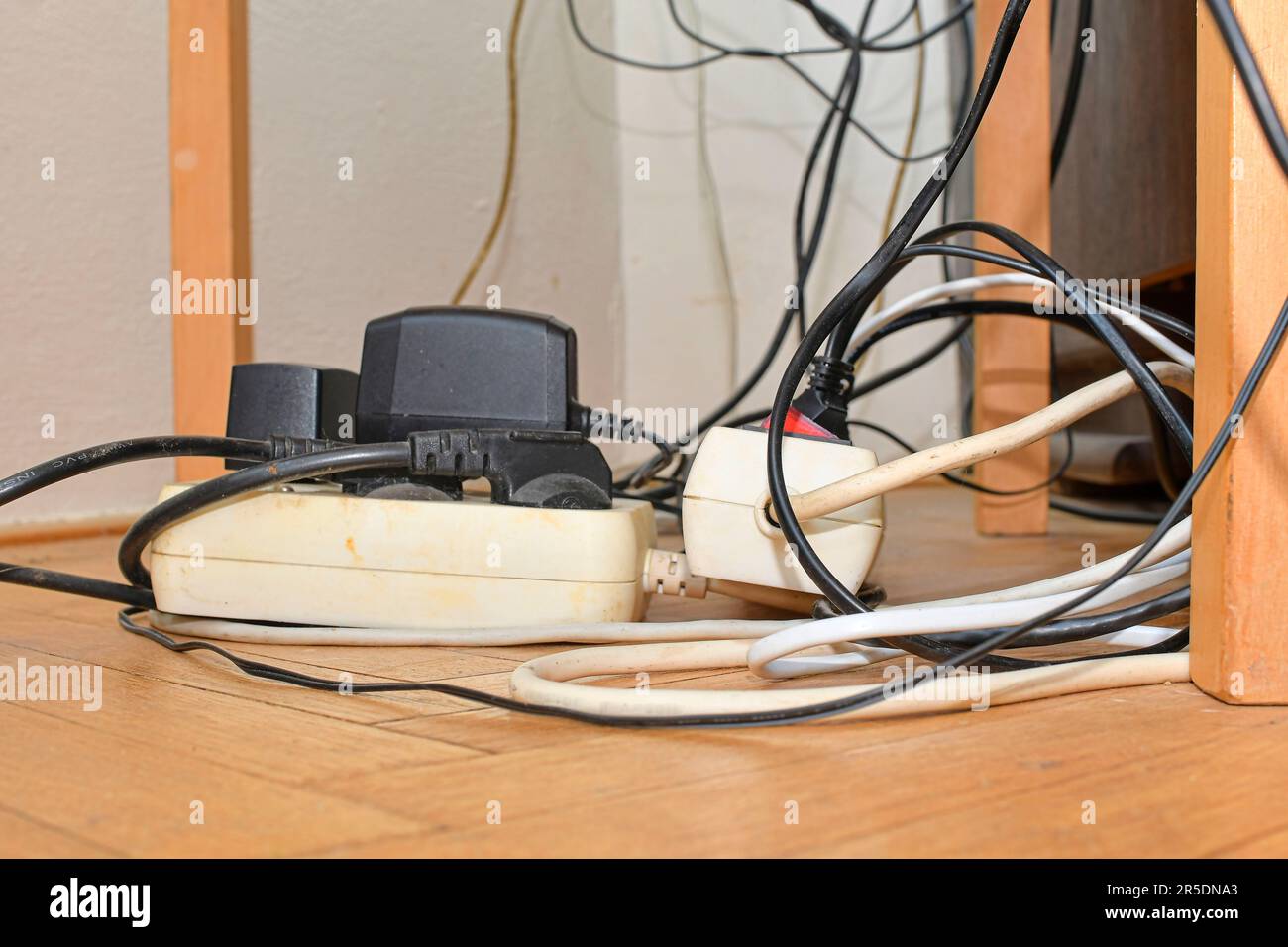 Tangled cables on the parquet floor. Overloaded electrical boards on ...