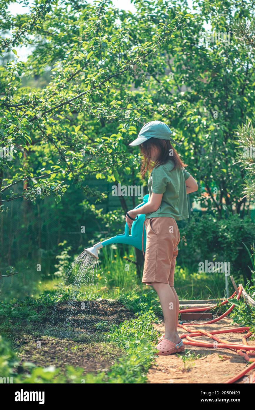 Little girl watering blooming tree with watering pot in the garden. Kid ...