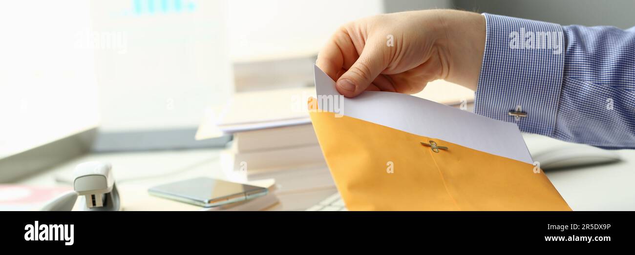 Businessperson opens yellow envelope with mail at workplace Stock Photo ...