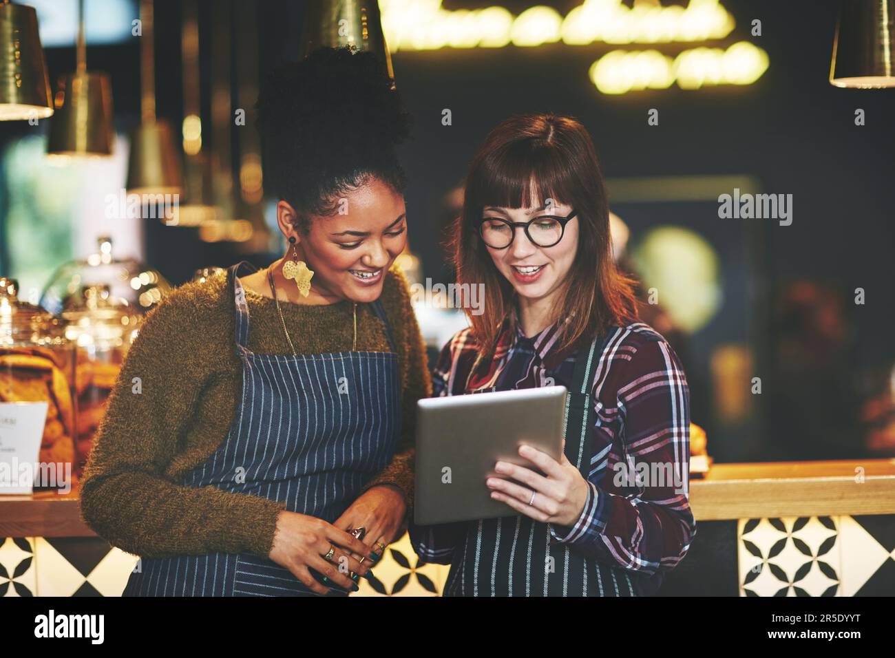 Marketing their cafe using good old social media. two young women using ...