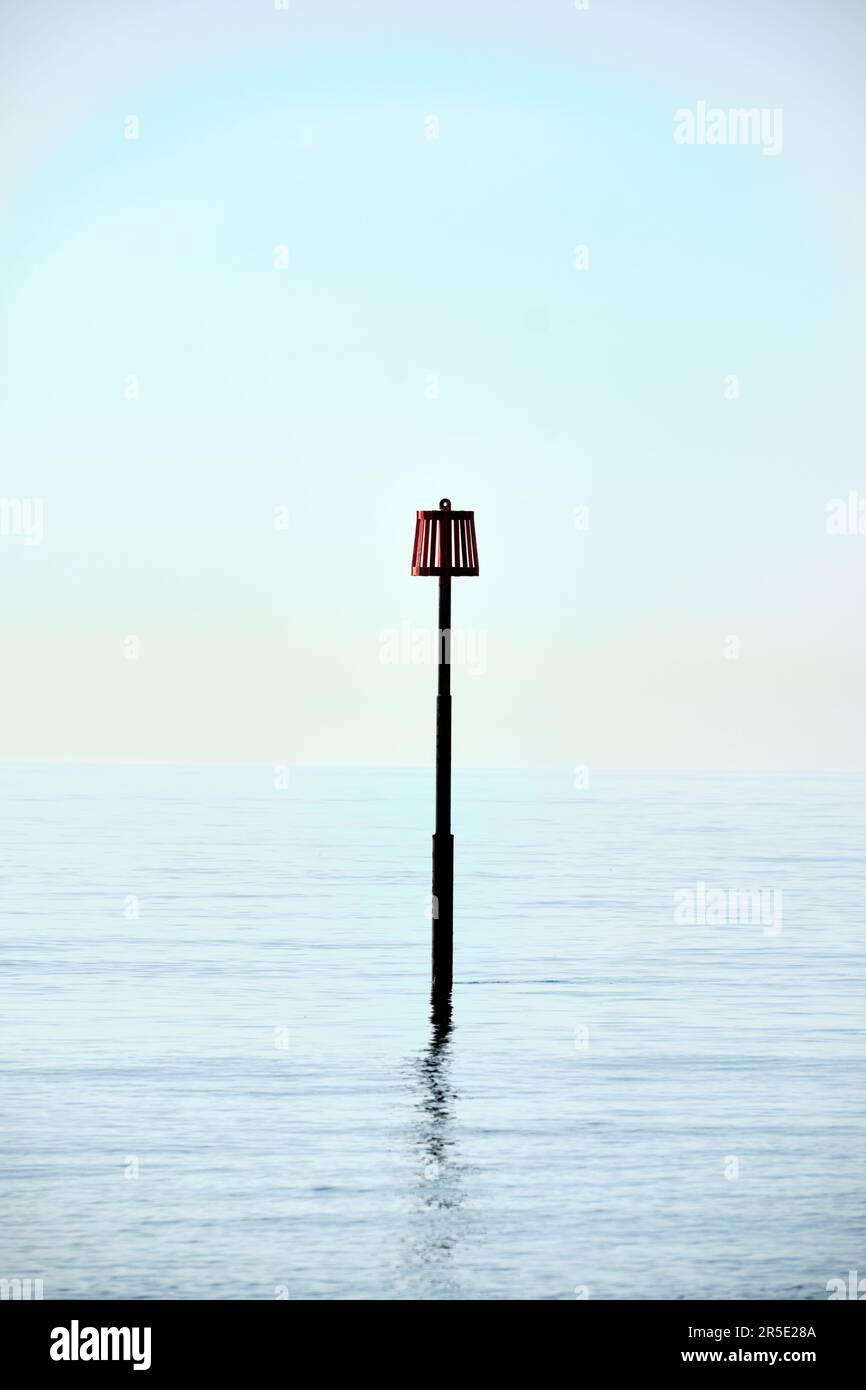 An isolated marker post off the beach in Eastbourne, East Sussex. Light ...