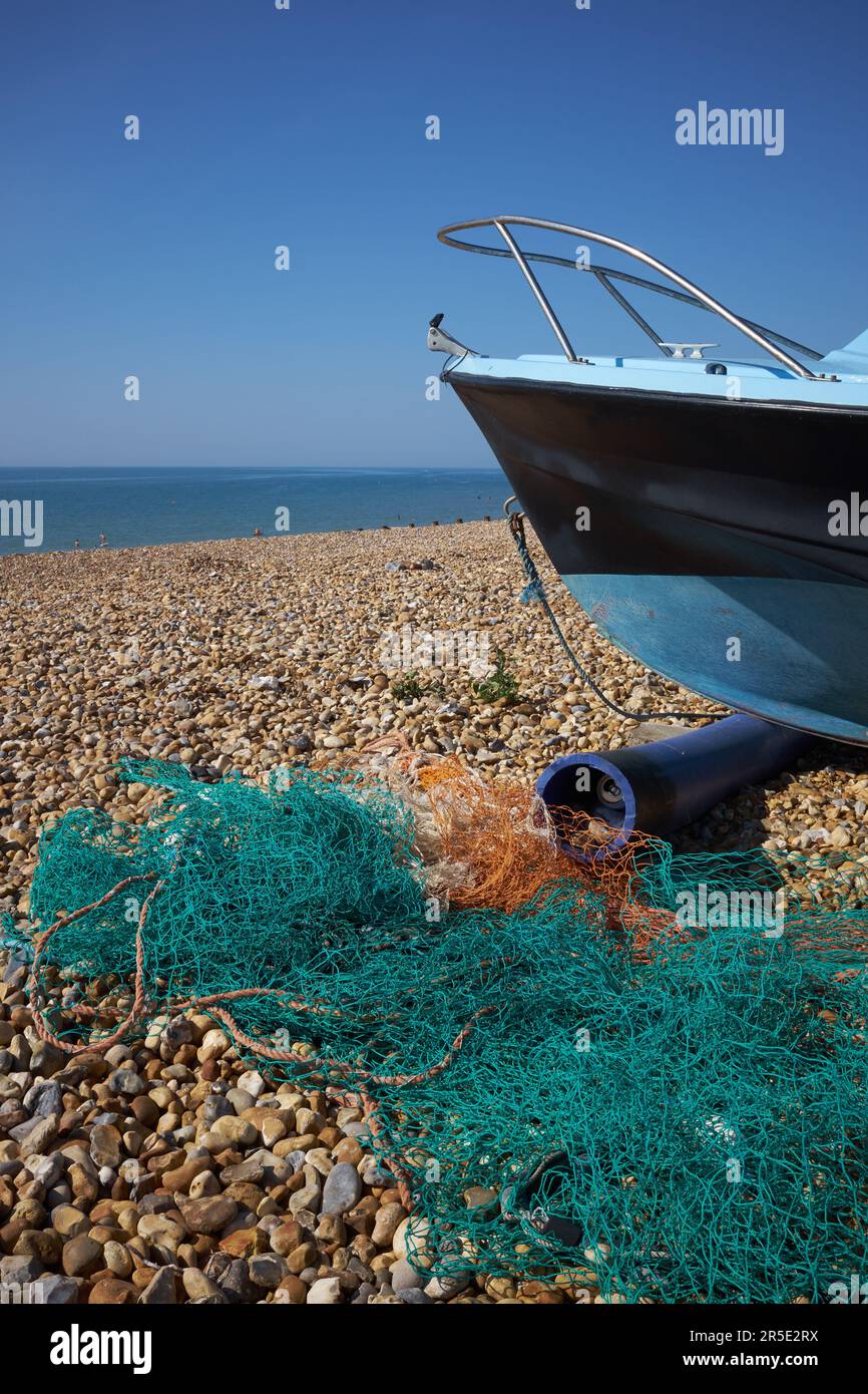 Turquoise and orange fishing net on a shingle beach next to a fishing ...
