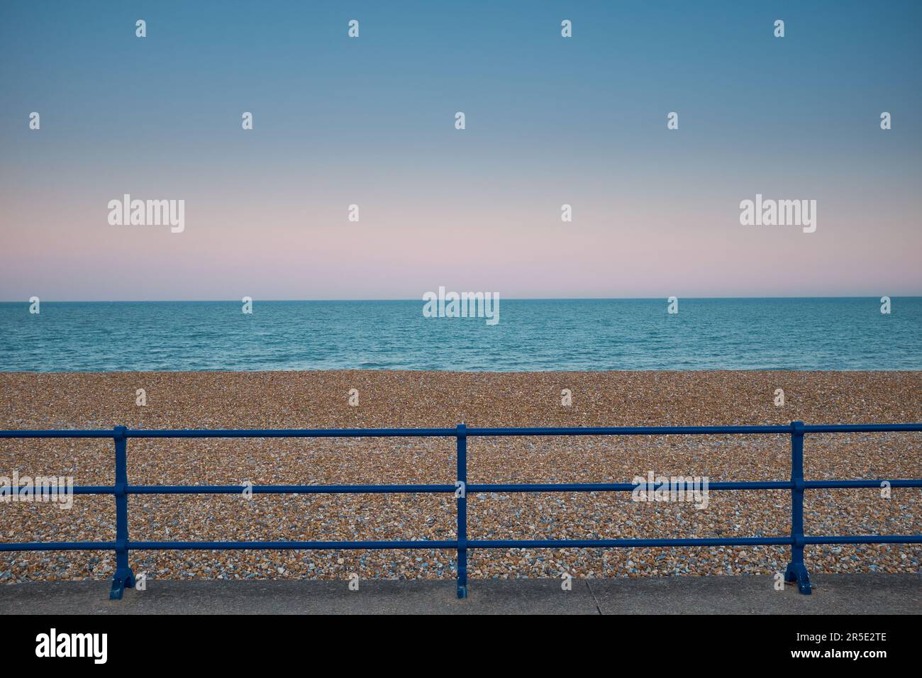 Blue painted metal railings in front of open, empty, shingle beach on ...