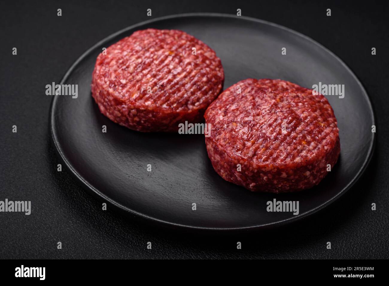 Fresh raw ground beef burger patty with salt and spices on textured ...