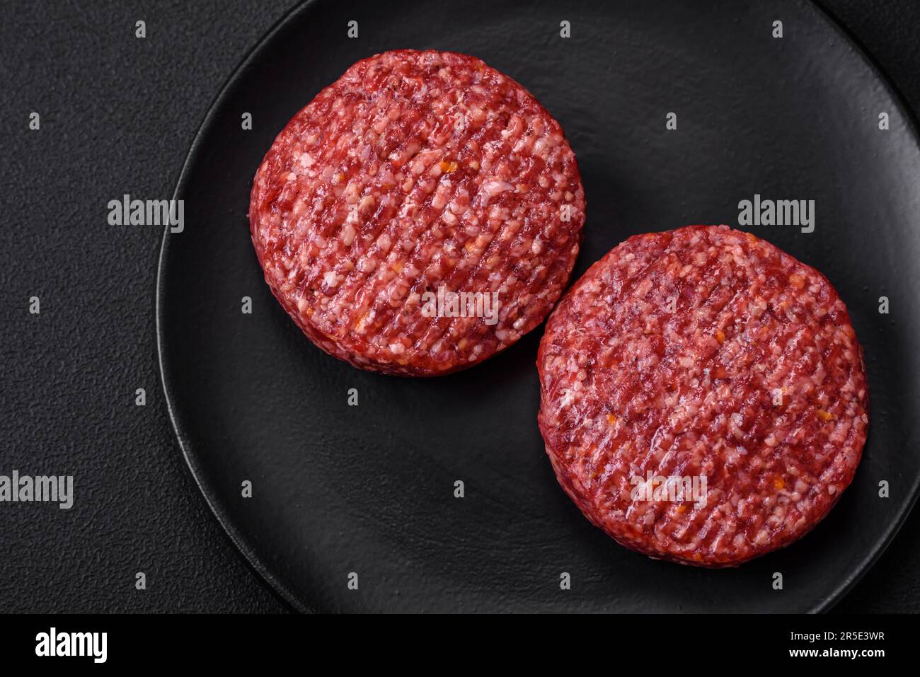 Fresh raw ground beef burger patty with salt and spices on textured ...