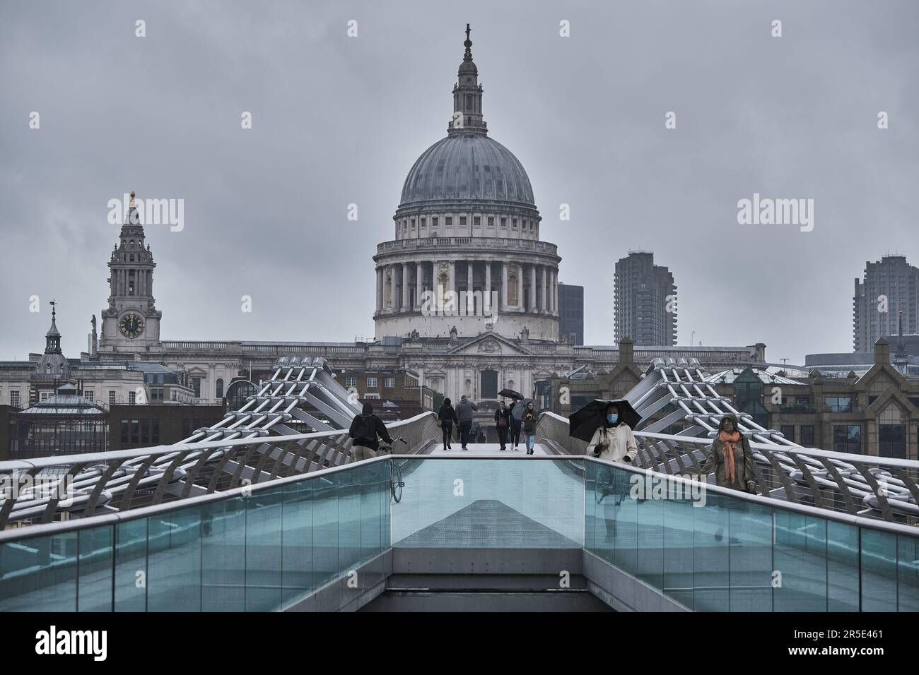 People walking over Millennium footbridge at dusk with London's city ...