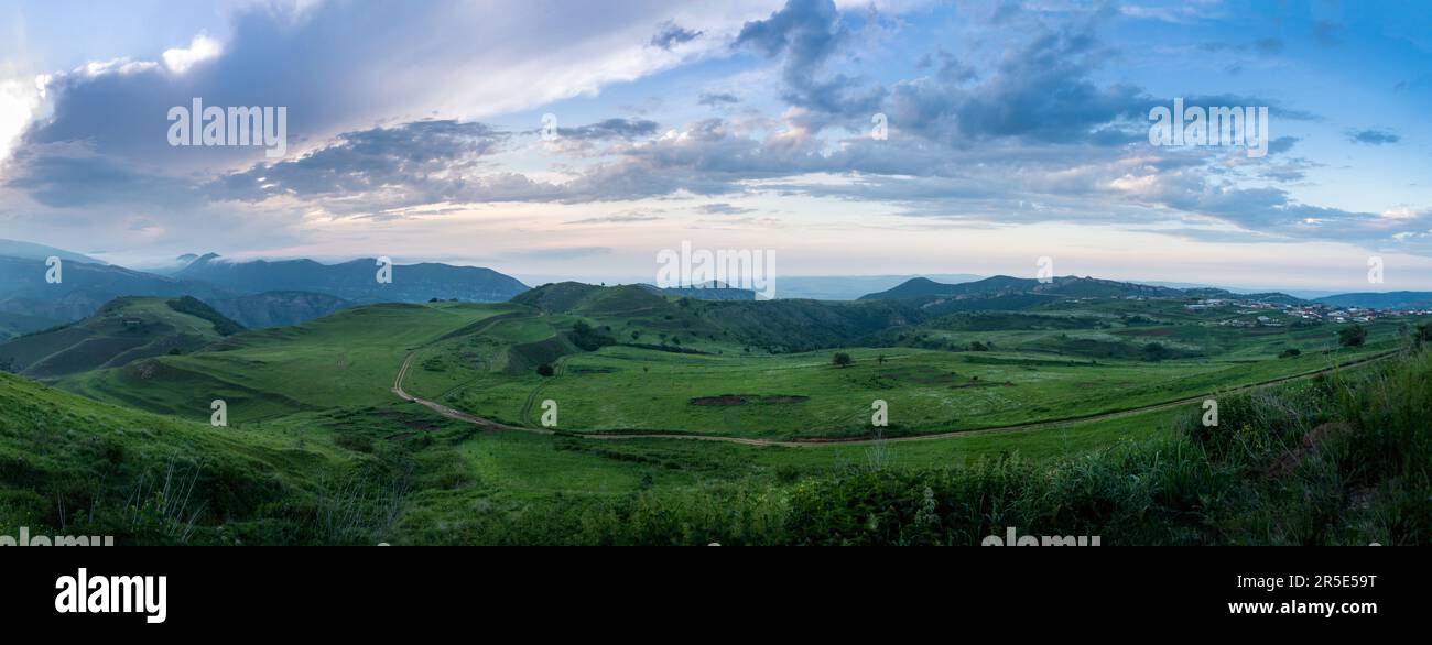 Panoramic view of Caucasus mountains and grasslands at sunset in the ...