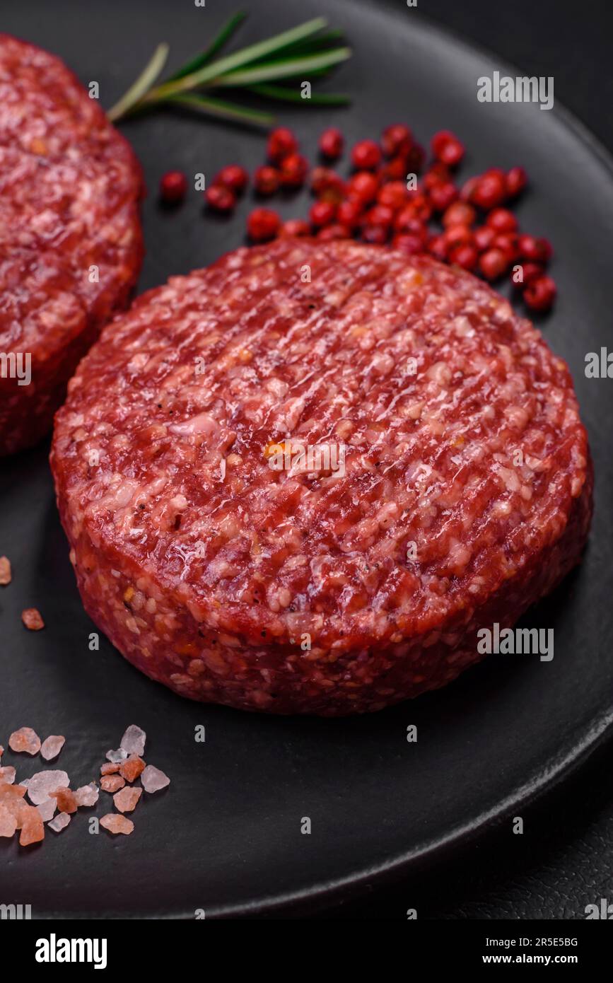 Fresh raw ground beef burger patty with salt and spices on textured ...