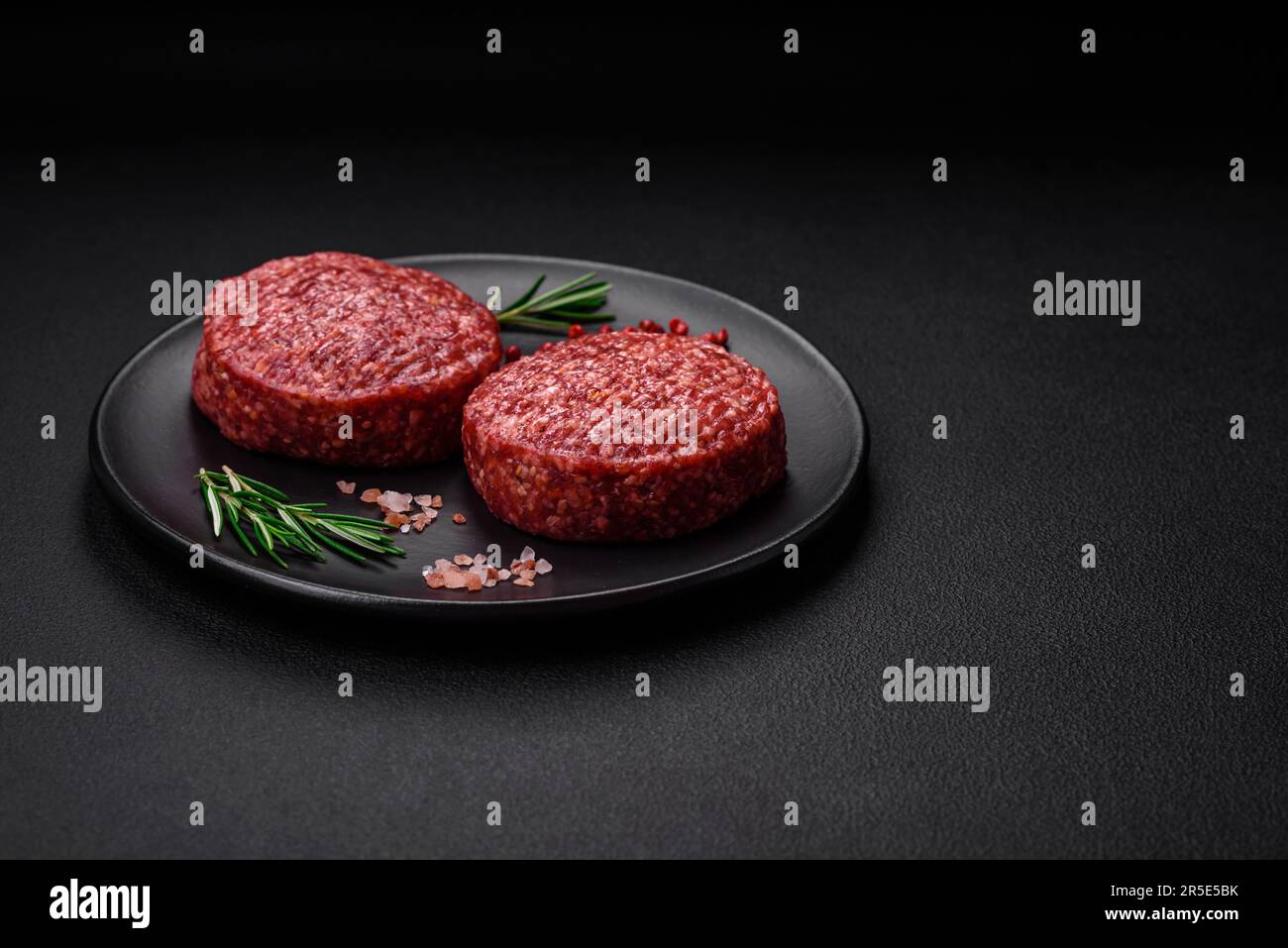 Fresh raw ground beef burger patty with salt and spices on textured ...