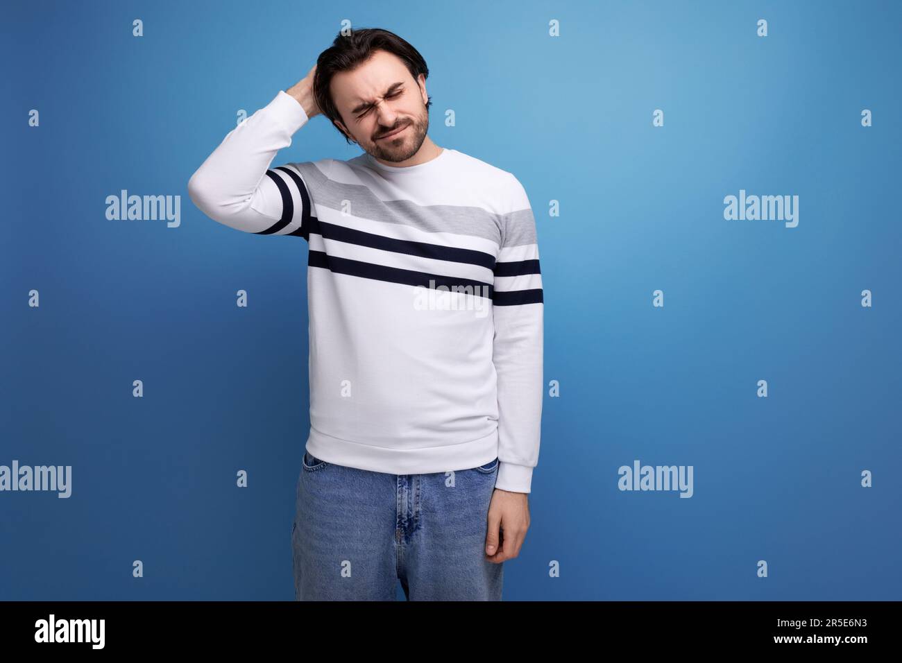 handsome well-groomed young brunette man thinking while standing on a ...