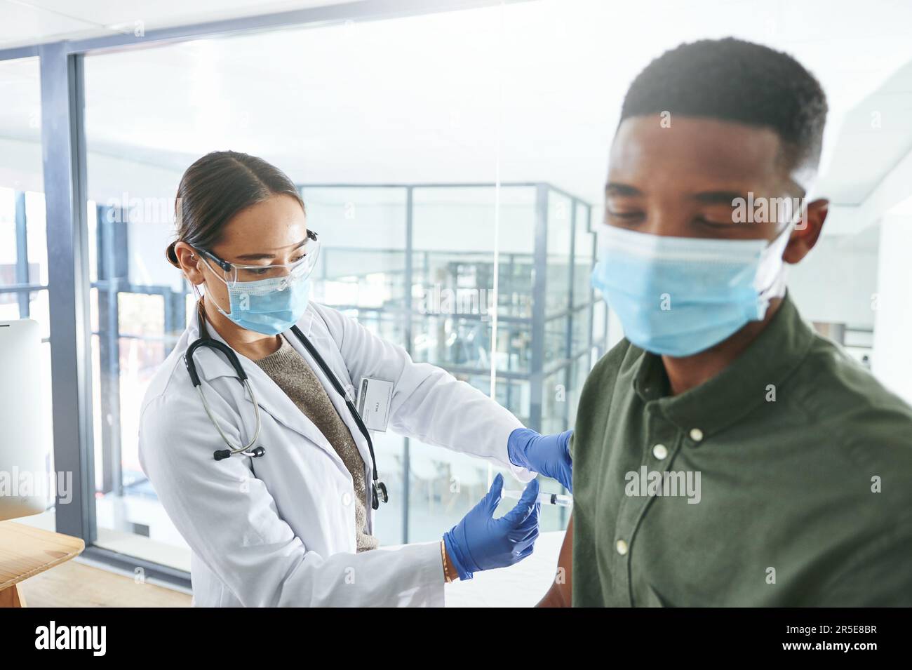 Just a quick jab. a young doctor giving a patient an injection in an ...