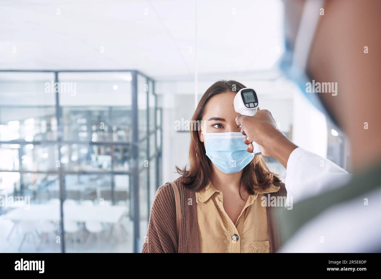 I hope you dont have a fever. a young woman wearing a mask and getting ...