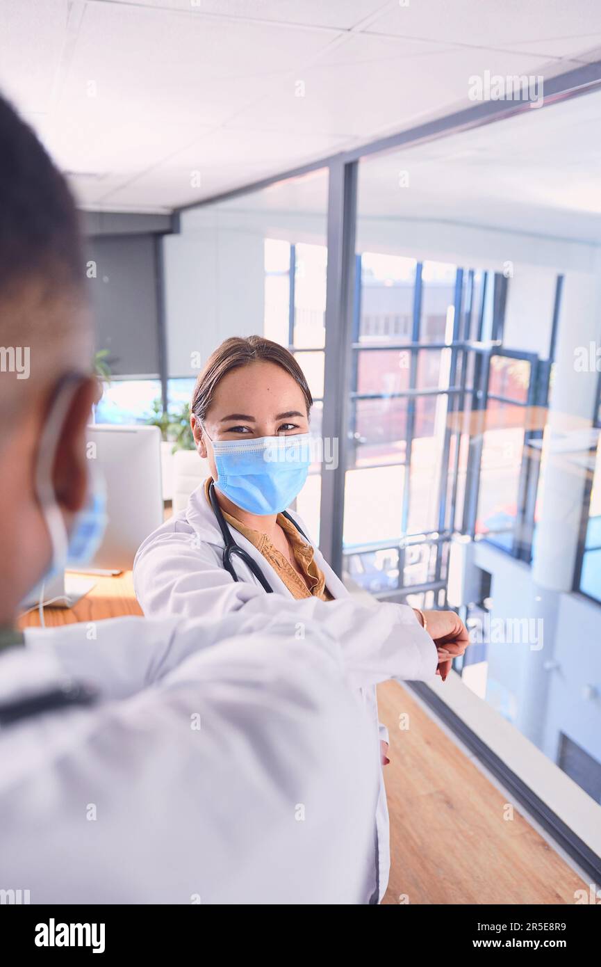 Good job. two unrecognizable doctors wearing masks and elbow bumping ...