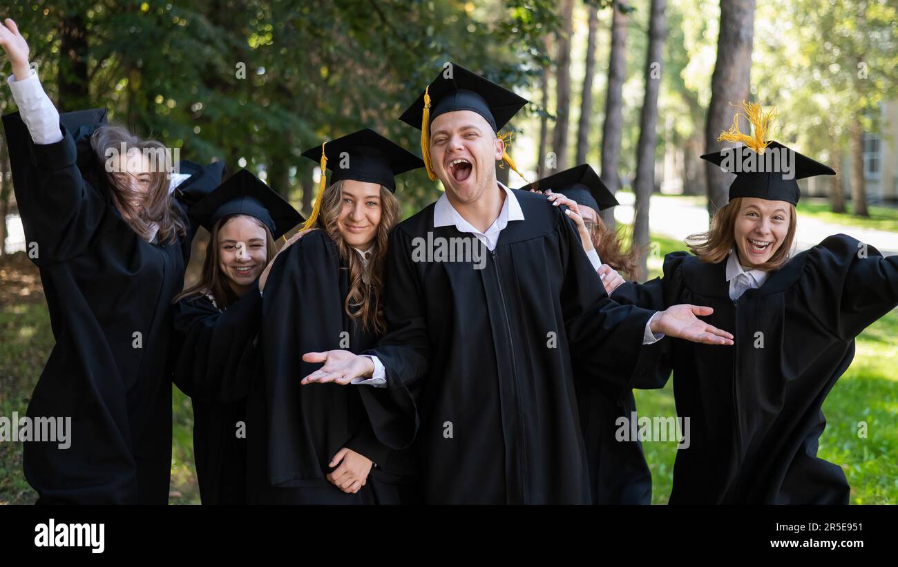 A group of graduates in robes congratulate each other on their ...