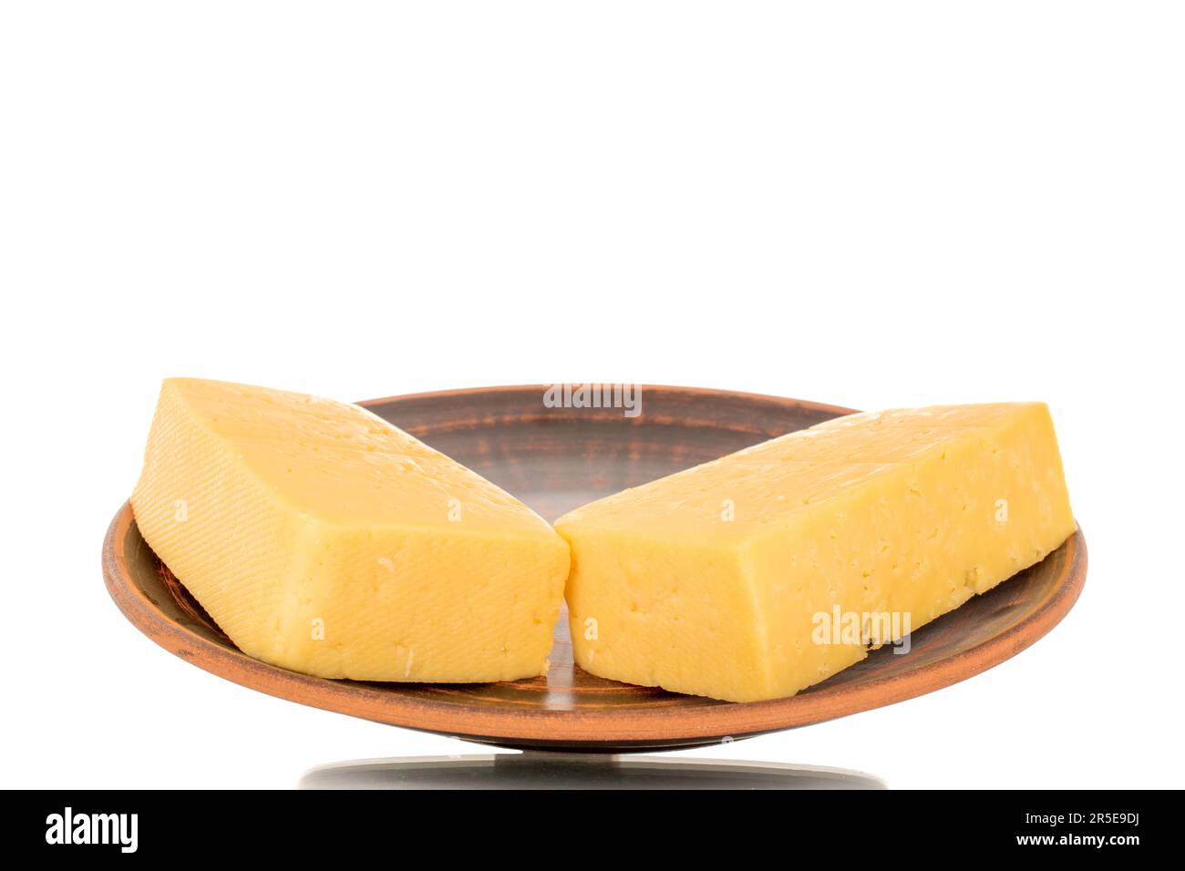 Two pieces of cheese on a clay plate, macro, isolated on white ...