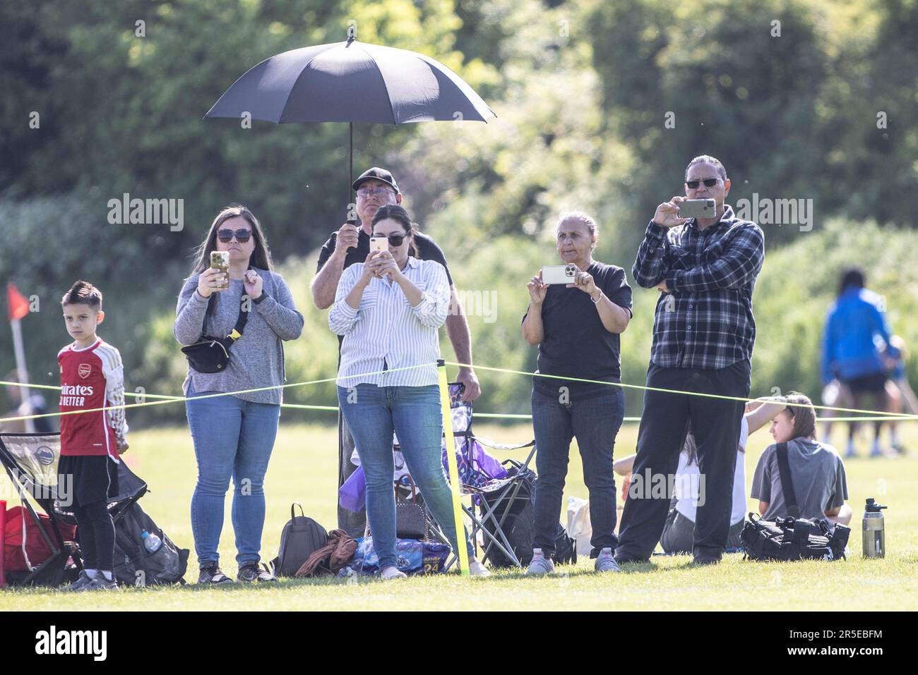 Parents watching children play grassroots football match and filming ...