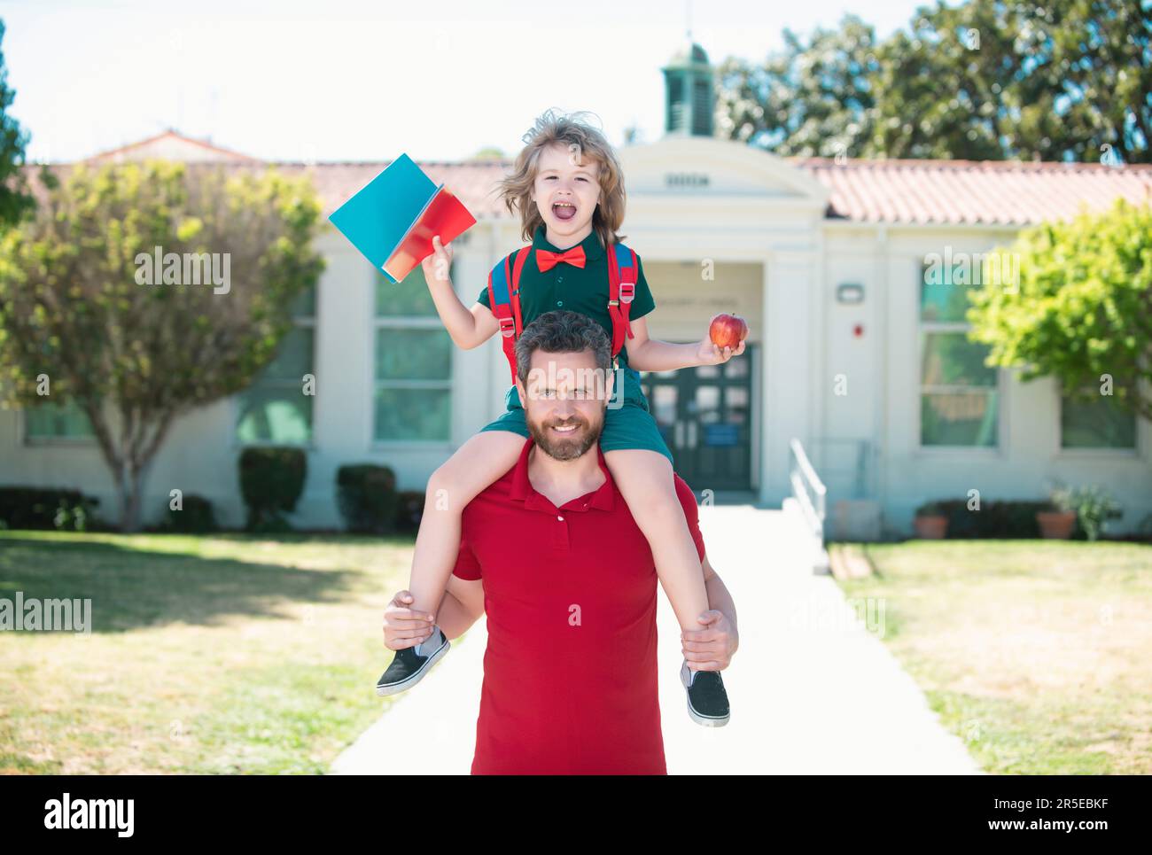 Father and son piggyback ride trough school park Stock Photo - Alamy