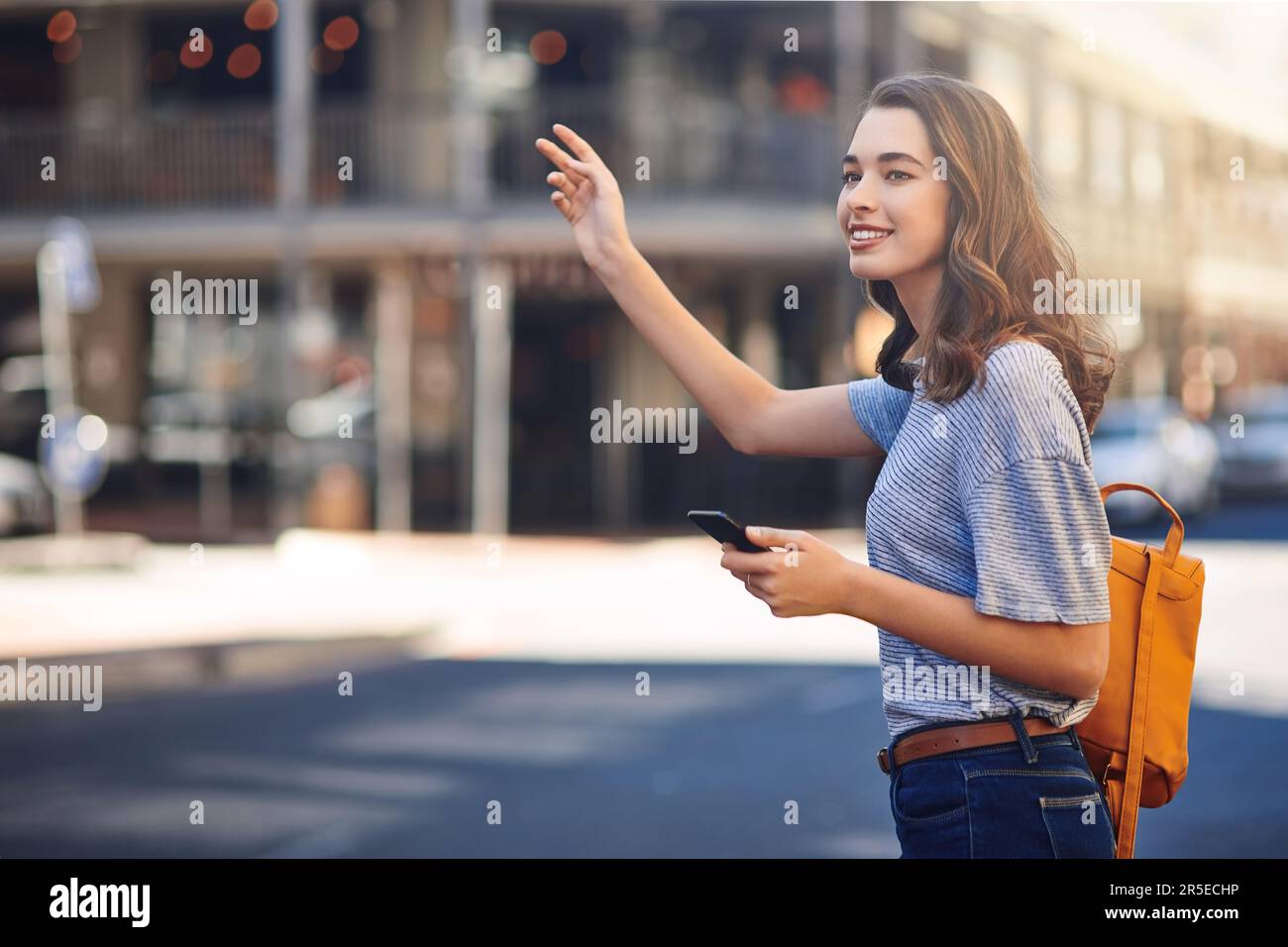Hailing a cab. an attractive young woman sending a text message while ...