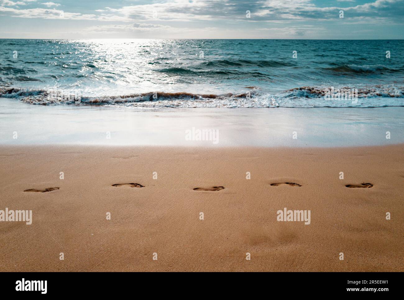 Footprints in the sand at sunset. Sandy tropical beach with sea waves ...
