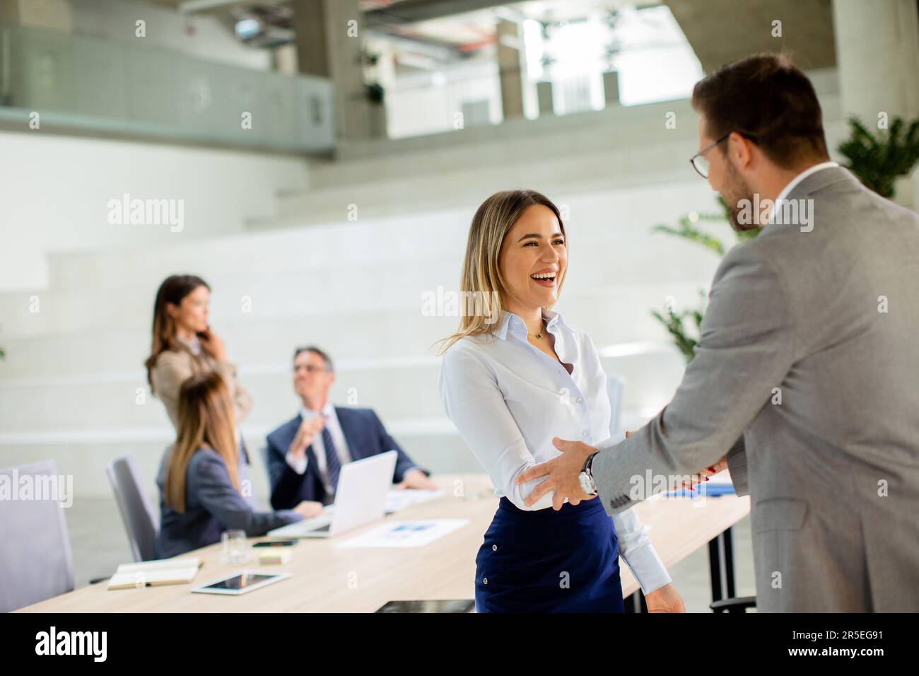 Pretty young business woman handshaking with his colleague in the ...