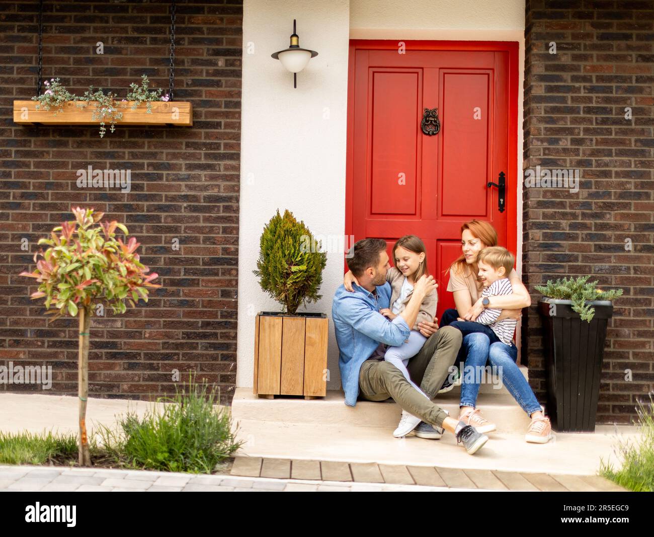 Family with a mother, father, son and daughter sitting outside on steps ...