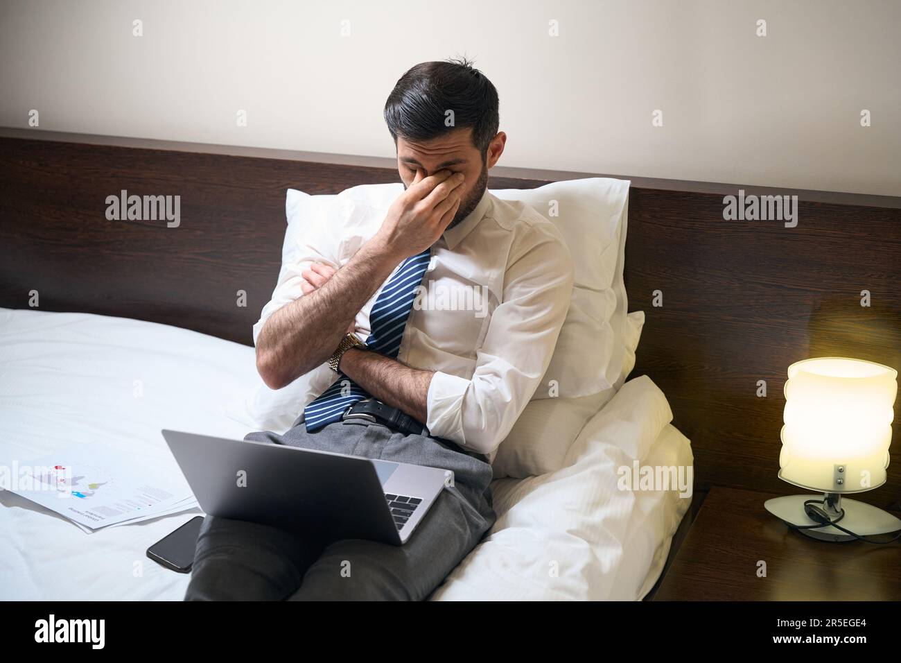 Tired male struggles with sleep while working on documents Stock Photo ...