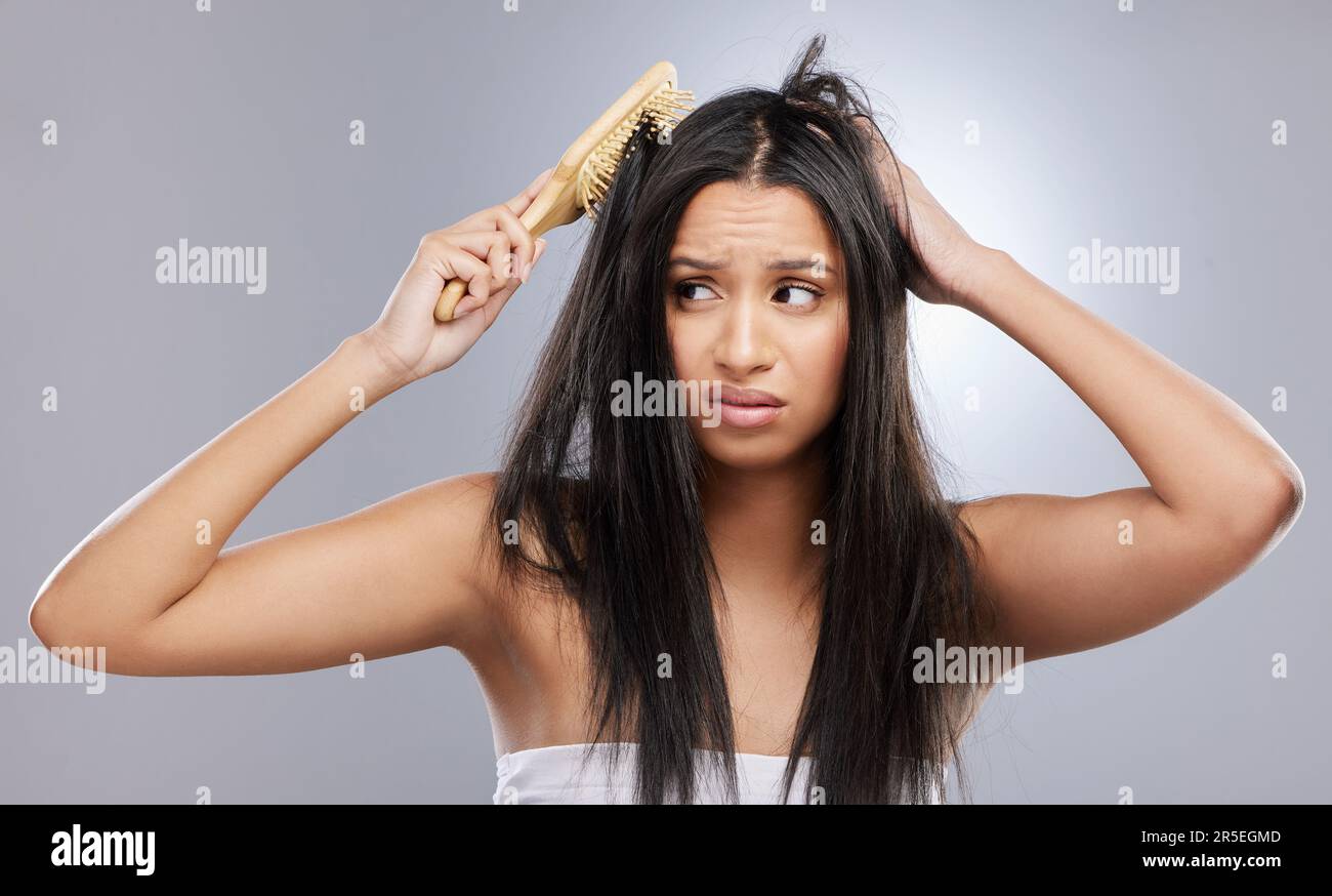 Hair, damage and woman with brush in studio with worry for knots ...