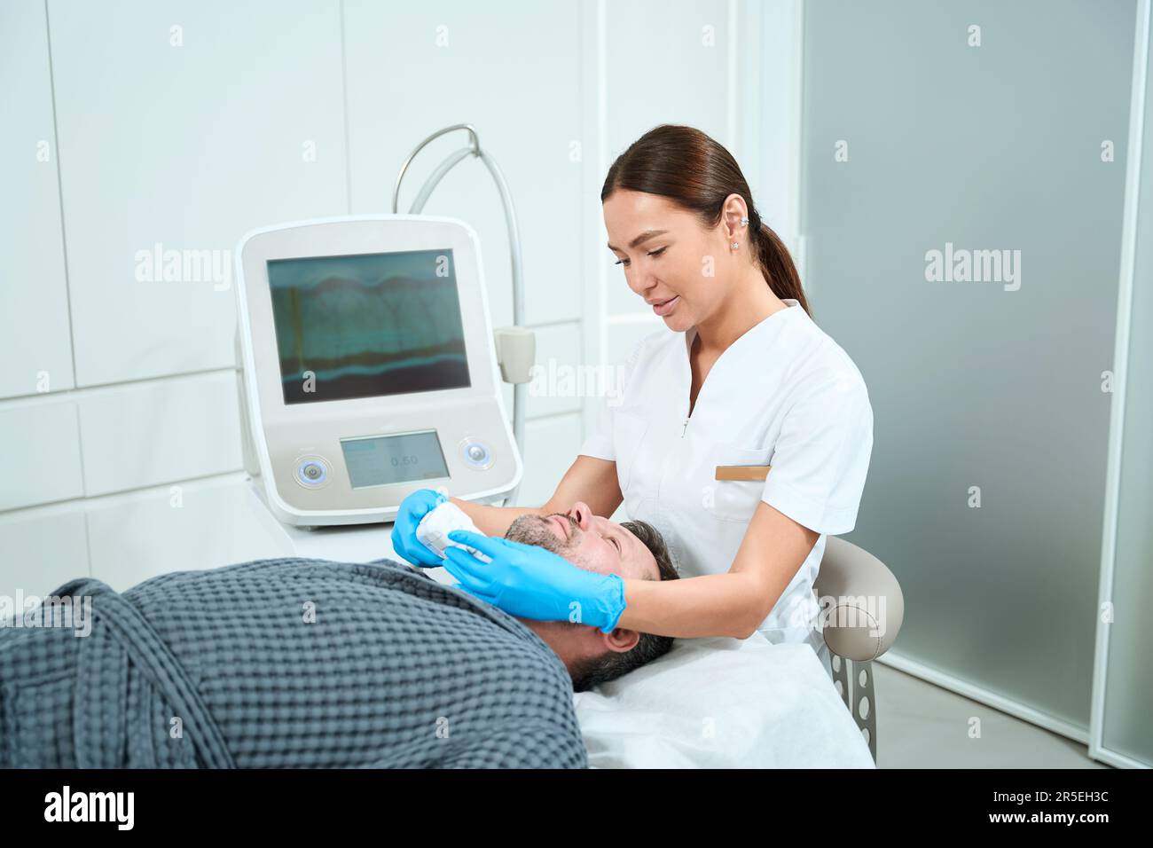 Pretty doctor performs mass lifting to a middle-aged man Stock Photo ...