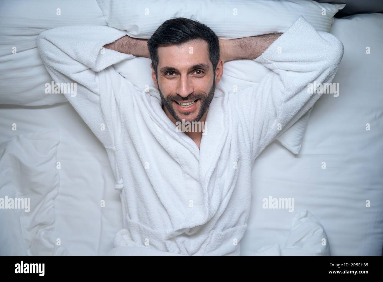 Happy rested man lies in bed in a hotel room Stock Photo - Alamy