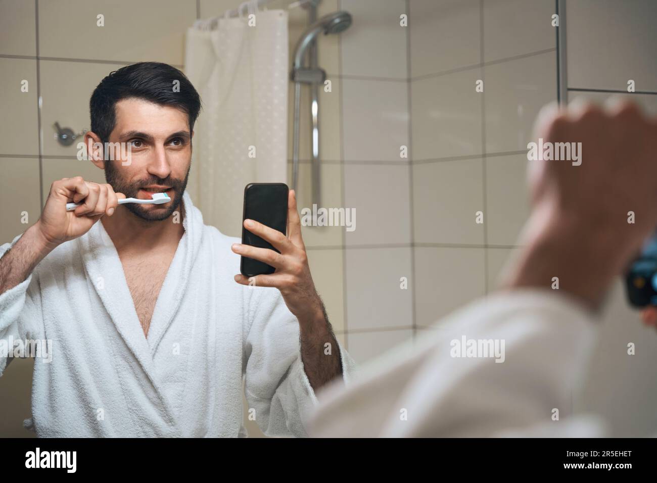 Handsome man brushing his teeth in front of camera phone Stock Photo ...