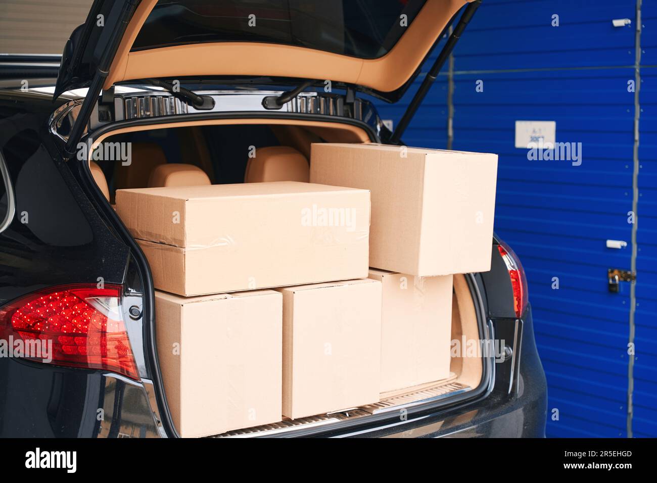 Cropped photo of car with cardboard boxes in the trunk into warehouse ...