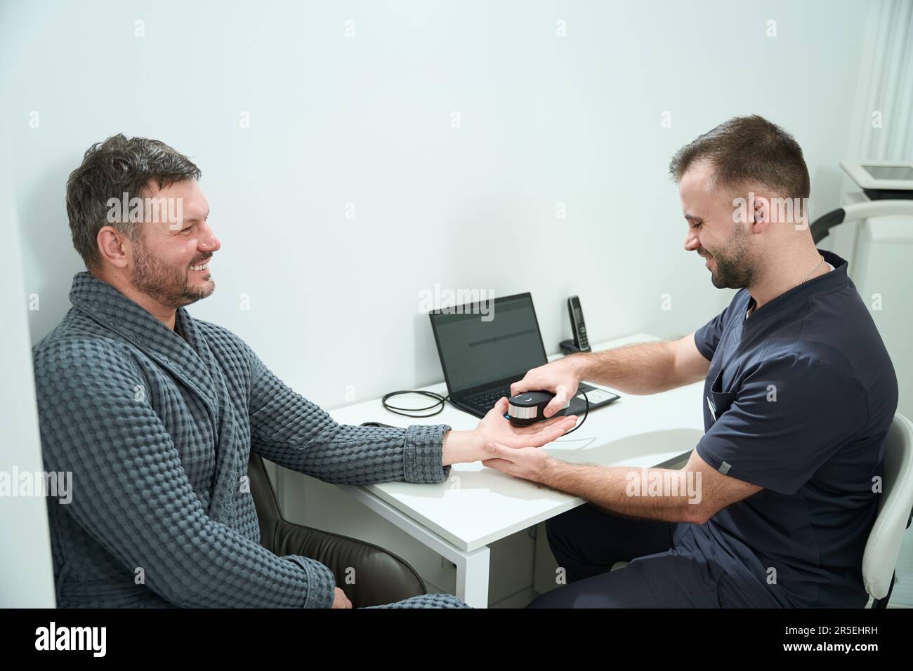 Bearded man in a medical center undergoes oligoscan diagnostic ...