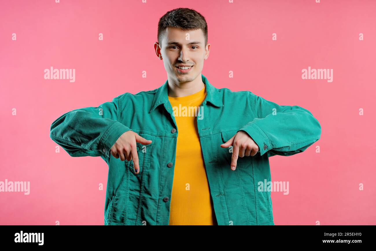 Happy man pointing down to advertising area on pink. Guy asking click ...