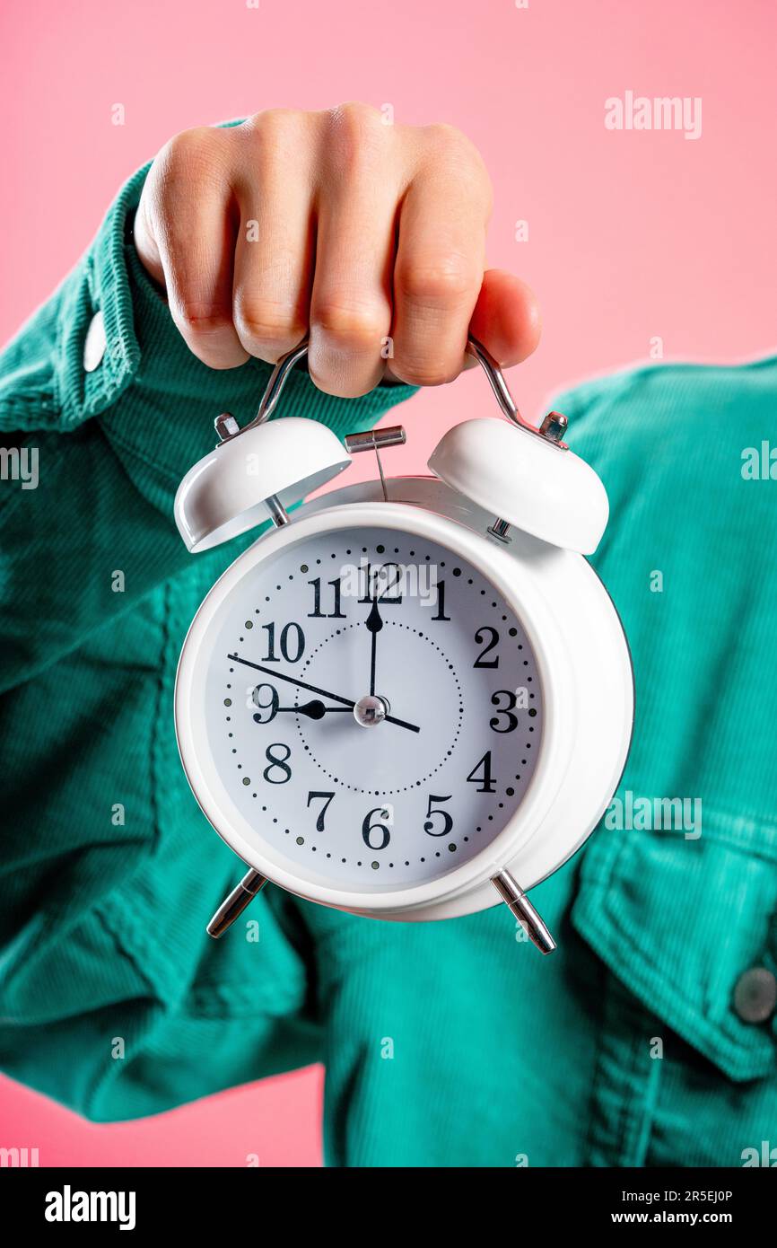 White alarm clock in male hand. Early morning, 9 o clock correct day ...