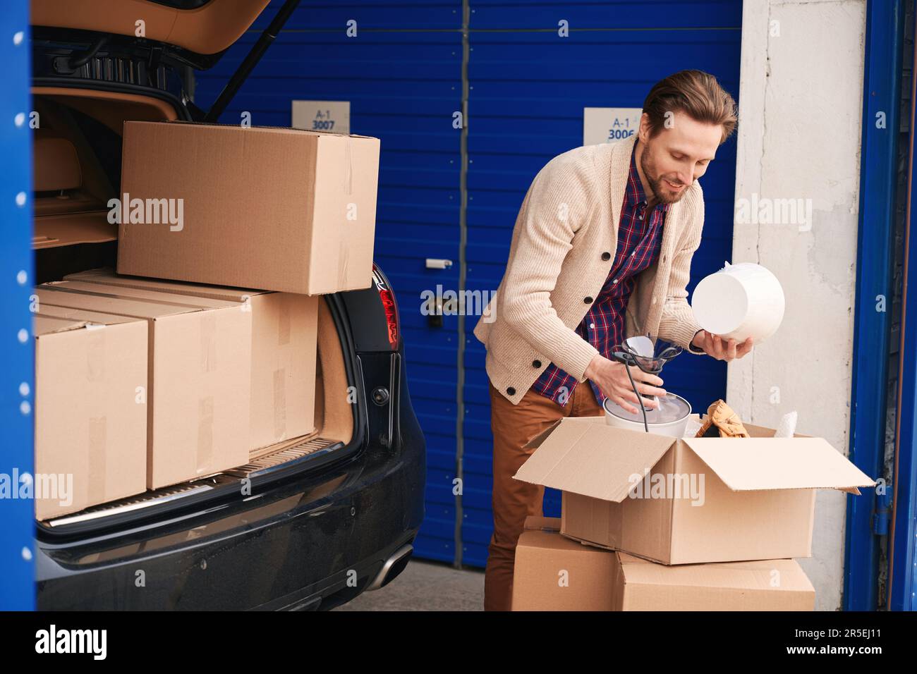 Young man is packing his things in cardboard boxes in the warehouse ...