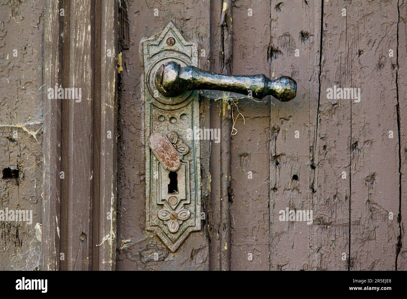 Old metal handle on ancient door with a spider web Stock Photo - Alamy