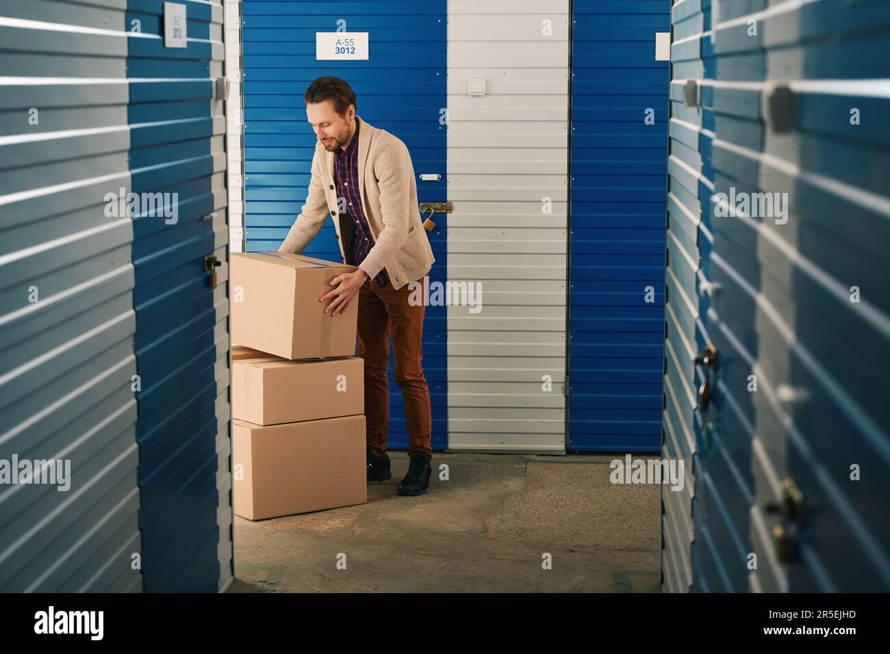 Guy with big cardboard boxes into warehouse with self-storage unit ...
