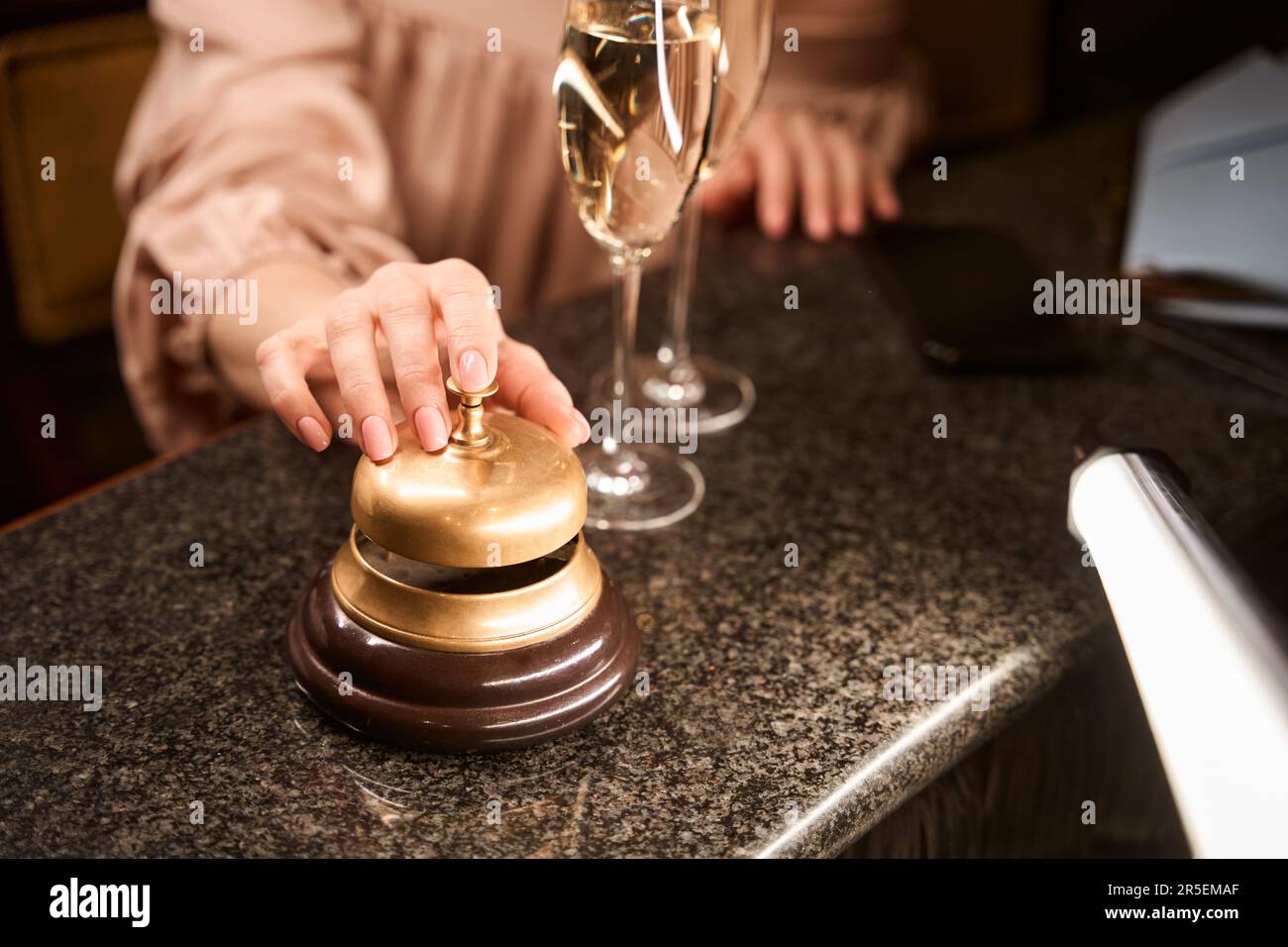 Female hand ringing golden bell for service at counter desk in the bar ...