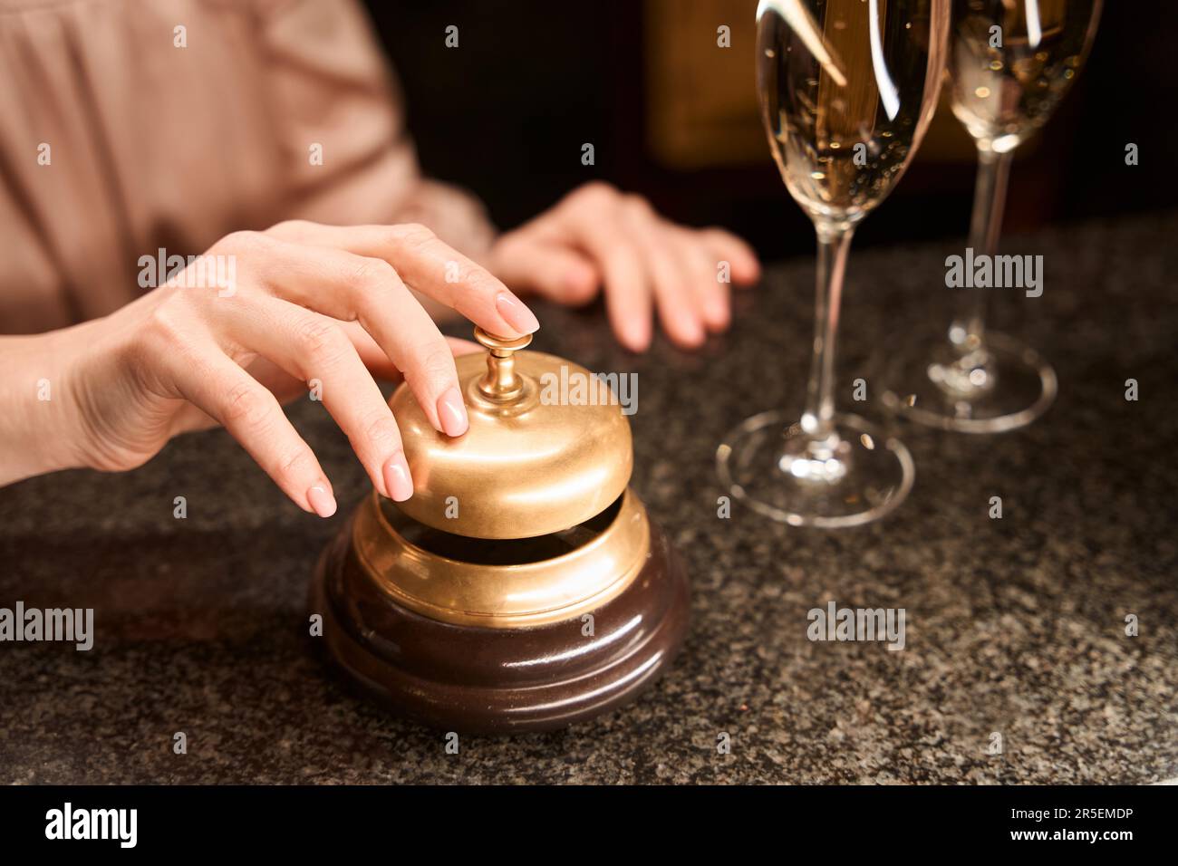 Female hand ringing golden service bell at counter desk in the bar ...