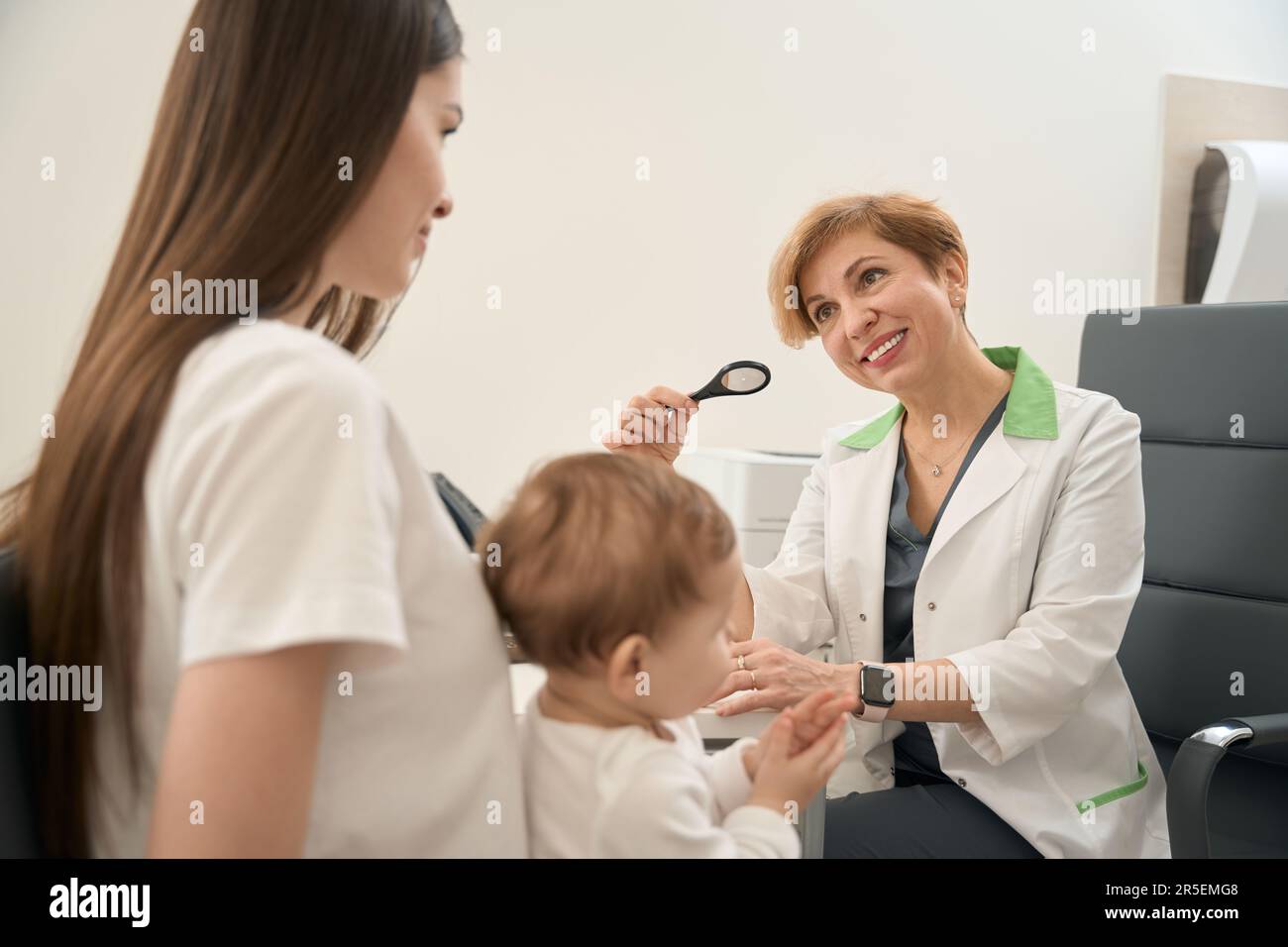 Friendly eye specialist giving initial consultation to woman with child ...