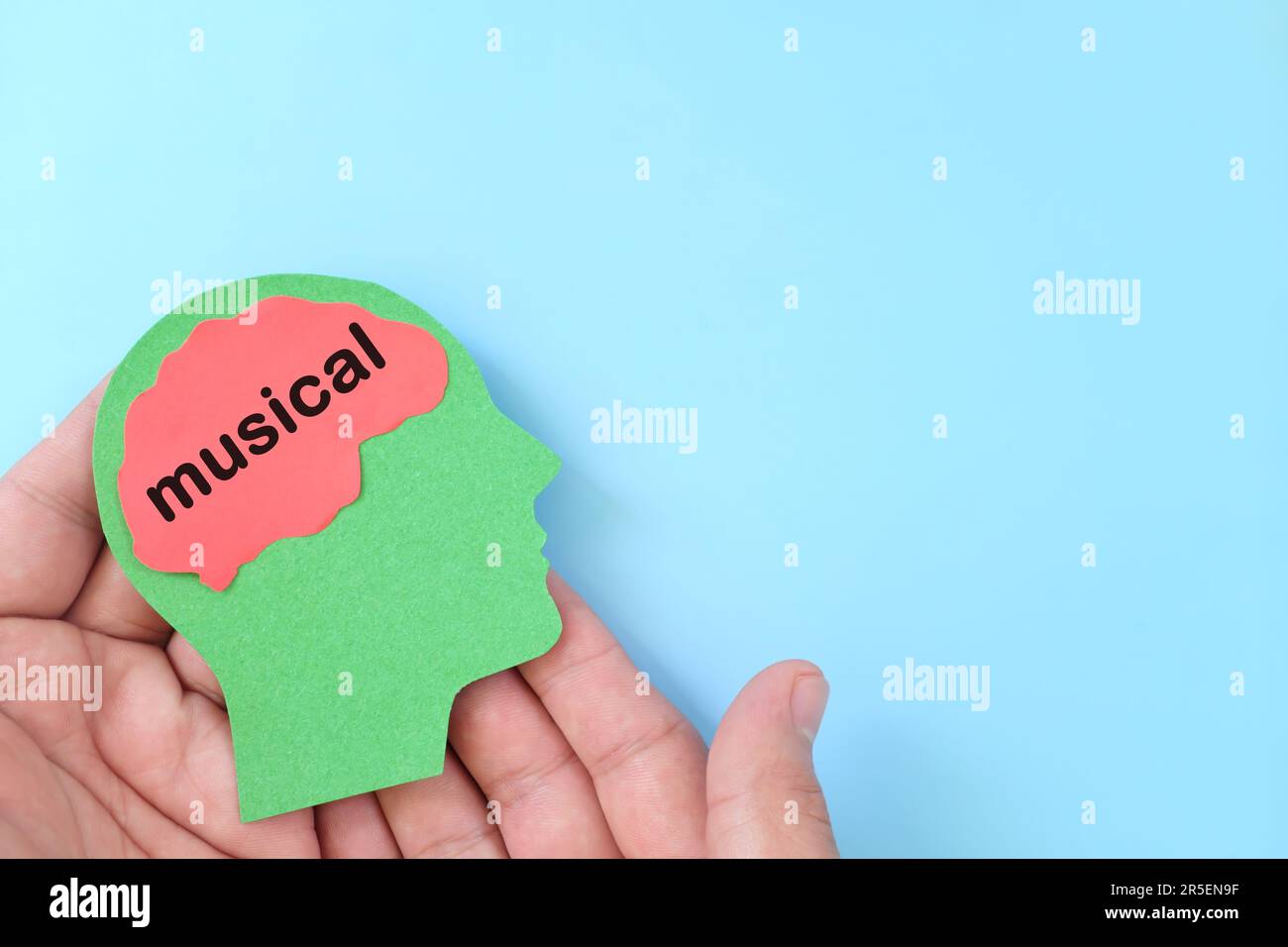 Musical intelligence in psychology concept. Hand holding human head ...