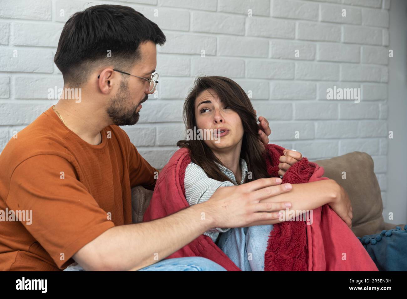 Couple at home. Handsome young man is calming his upset crying wife ...
