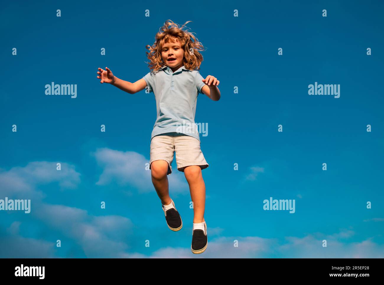Caucasian boy in a park running and smiling on blue sky. Happy kid ...