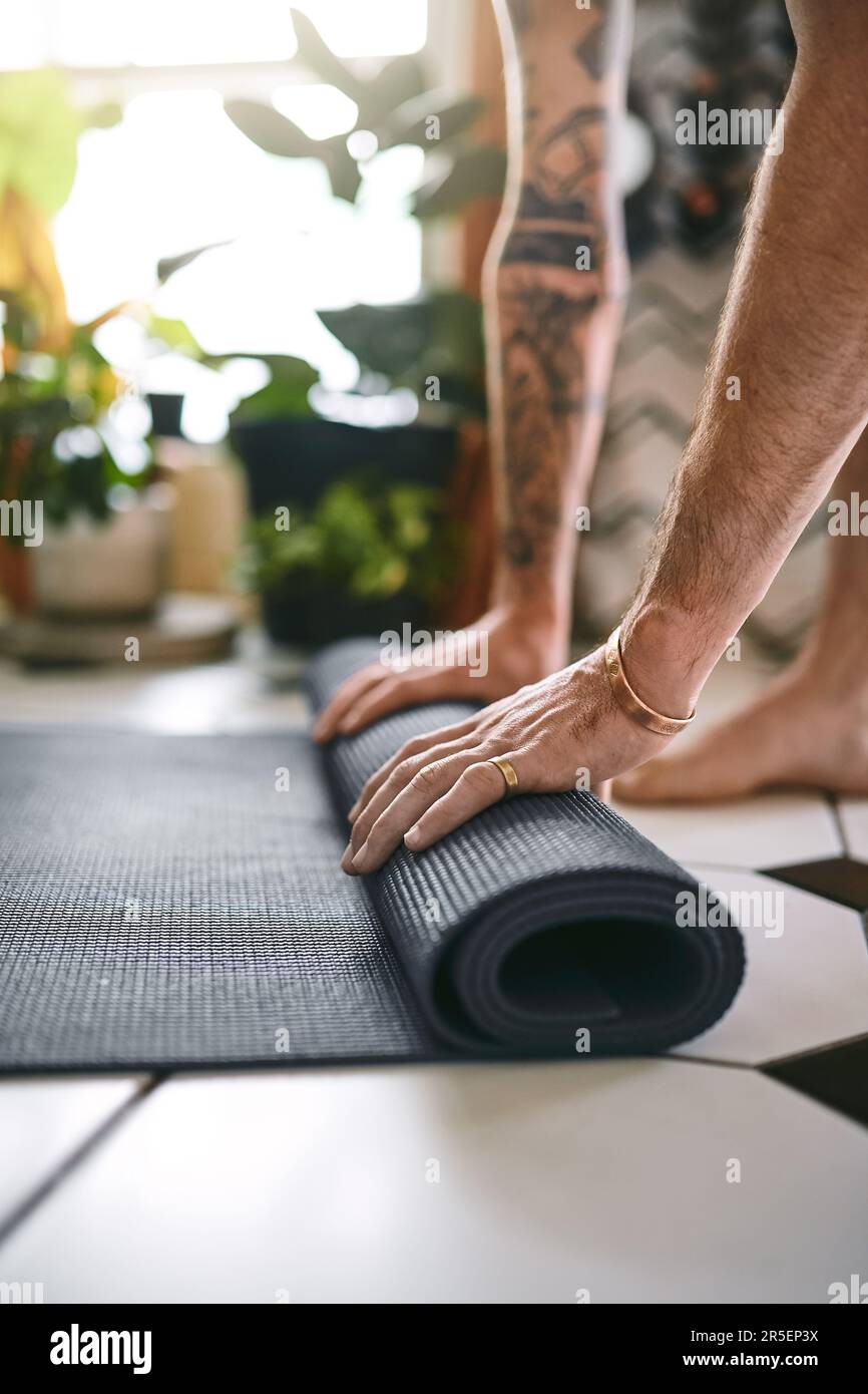 Yoga keeps you grounded. an unrecognisable man rolling up his yoga mat ...