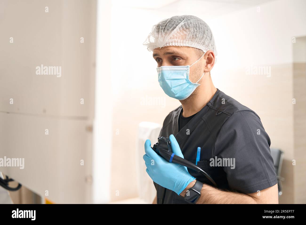 Serious doctor carrying out endoscopic ultrasound in procedure room ...