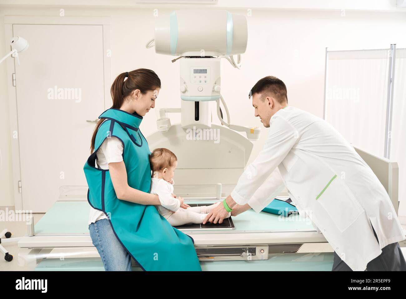 Qualified radiographer preparing toddler for x-ray of lower extremity ...
