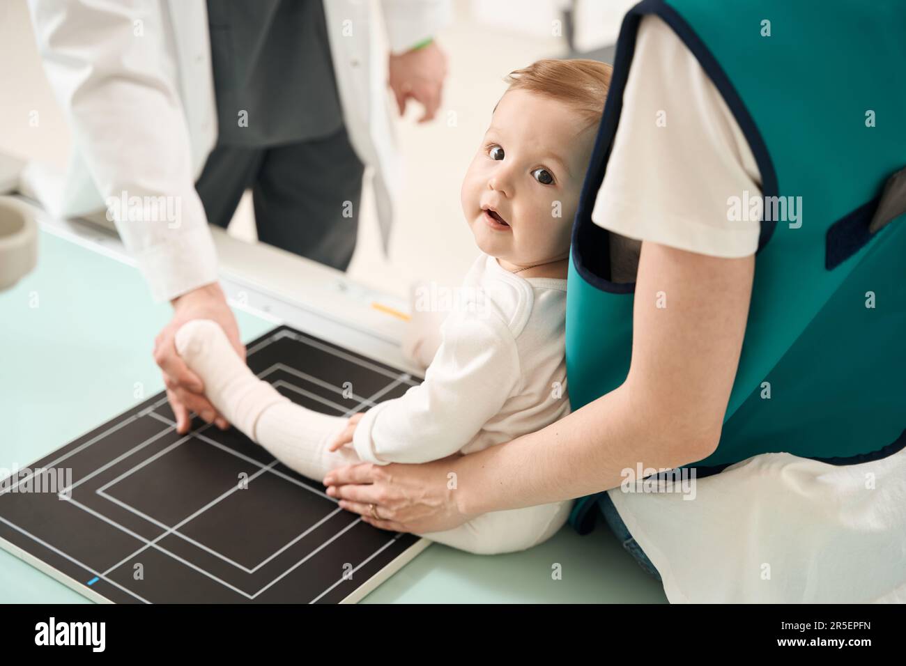 X-ray technician preparing small child for lower limb radiography Stock ...