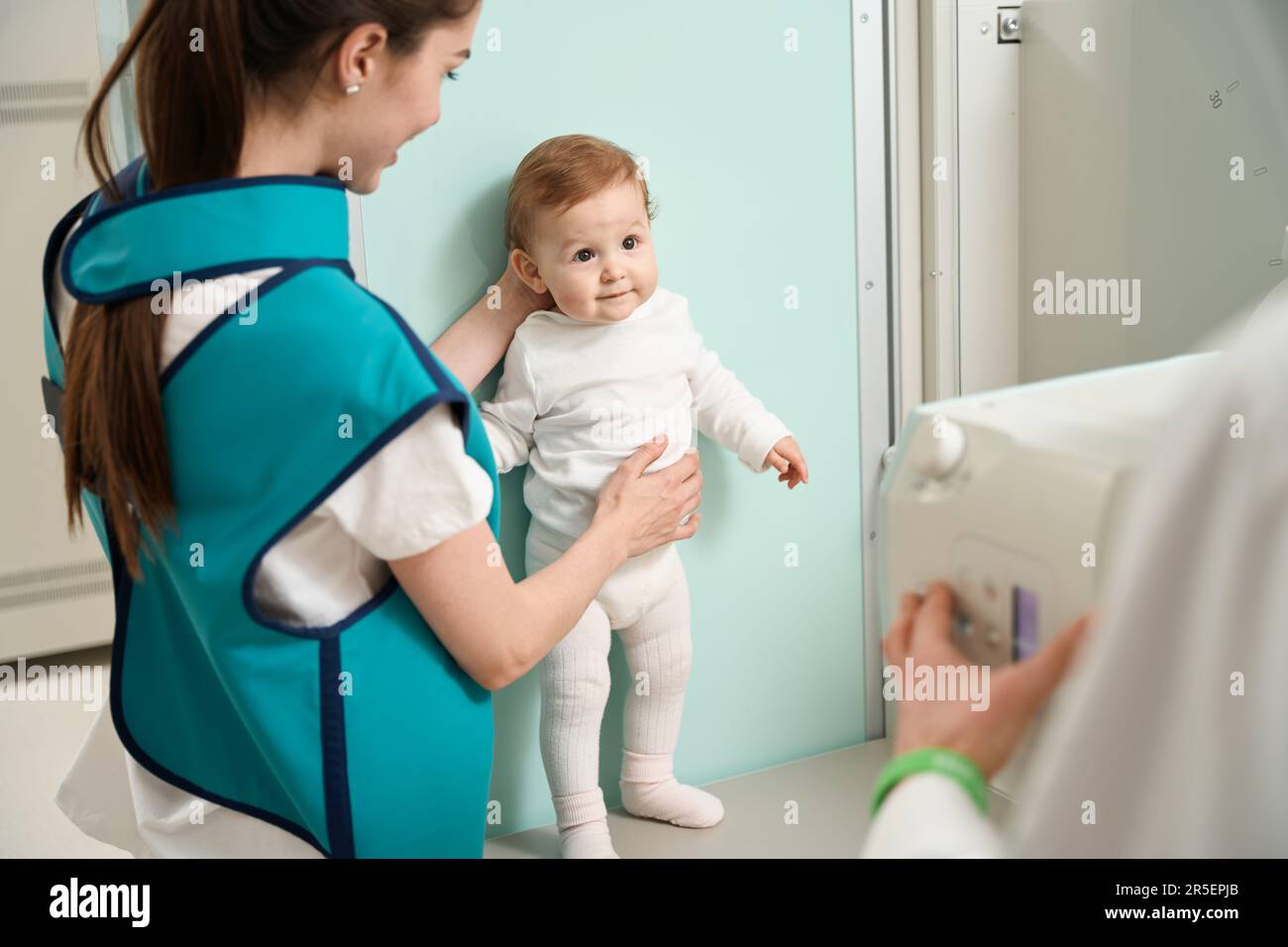 Little child undergoing radiography procedure performed by radiographer ...