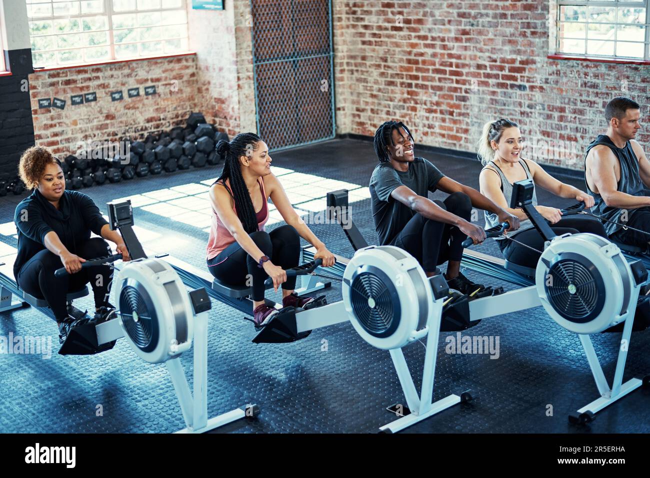 Keep pushing forward. a fitness group working out on rowing machines in ...
